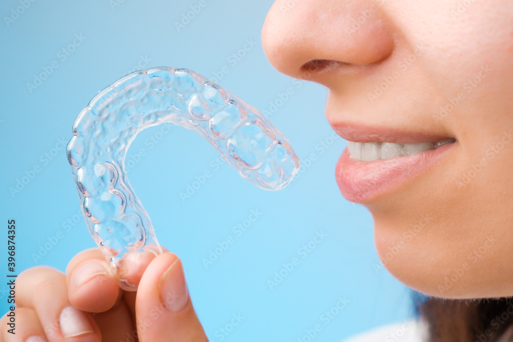 Close up woman holding a transparent removable braces for perfect smile ...