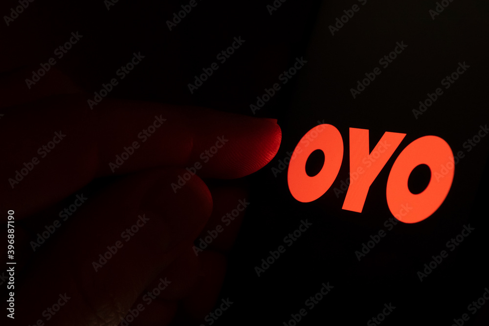 OYO hotel booking app logo on the screen and finger pointing at it ...