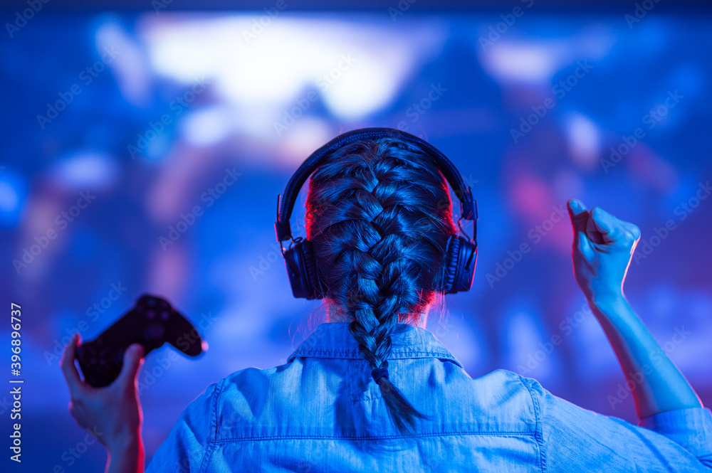 View from back of young gamer woman with pigtail playing video game at ...