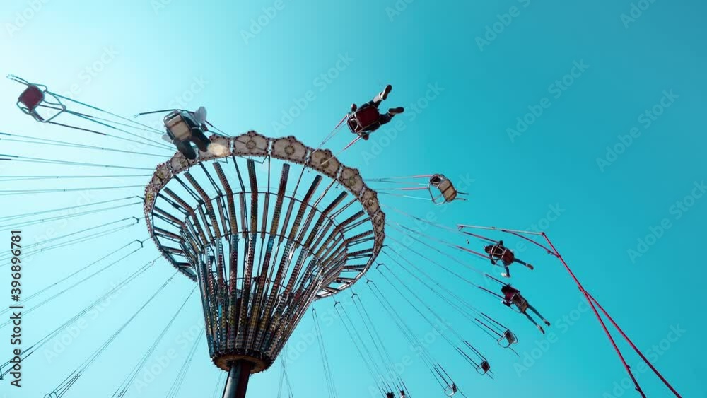 A rotating chair swing ride carousel with teenagers enjoying the ride ...