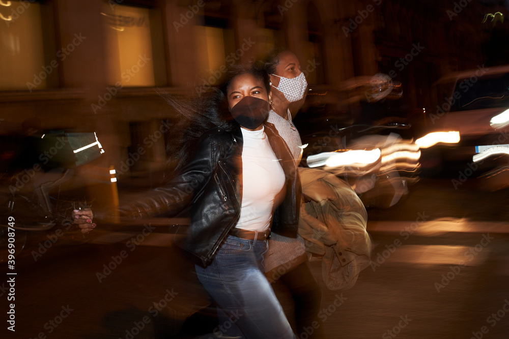 Flash portrait of two African American women with face masks running ...