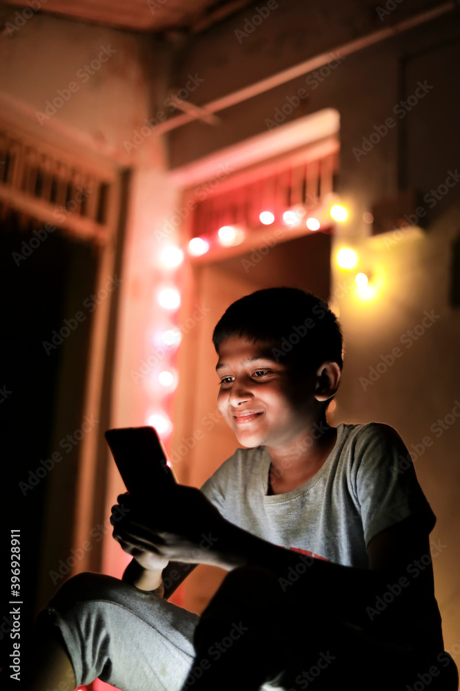Cute indian little child using smart phone with lighting background ...