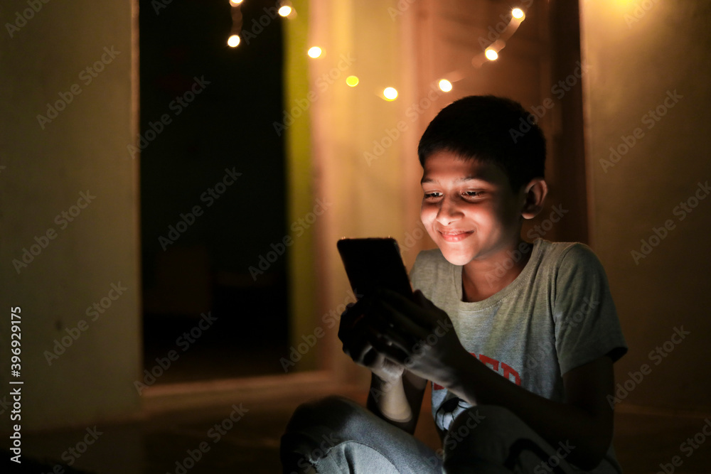 Cute indian little child using smart phone with lighting background ...