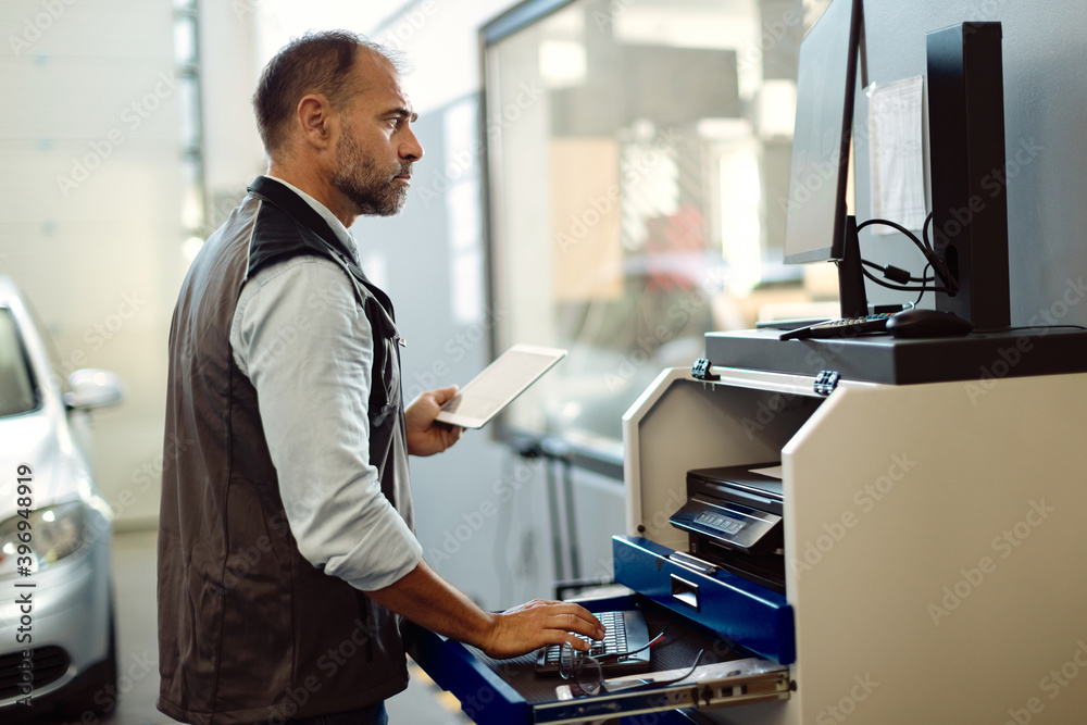Auto mechanic using touchpad and desktop PC while working in a repair ...