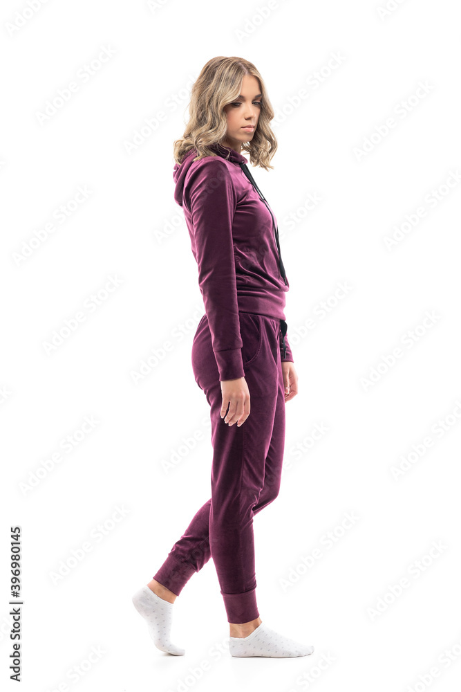 Side view of serious walking young beauty woman in leisure wear looking ...