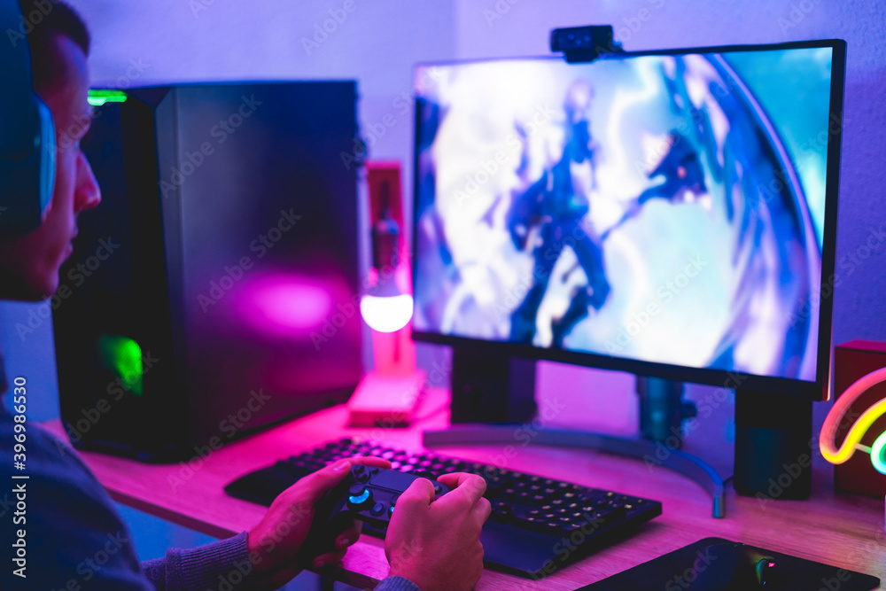 Gamer playing at computer game using joypad - Young man streaming ...