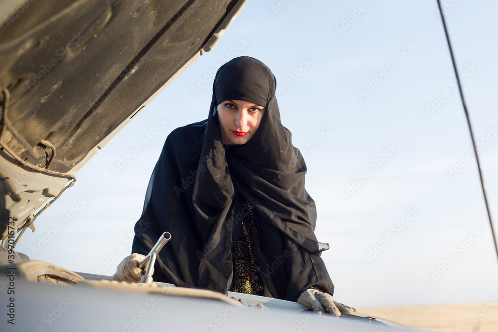 Muslim woman driver repairs a car in traditional dress. Stock Photo ...