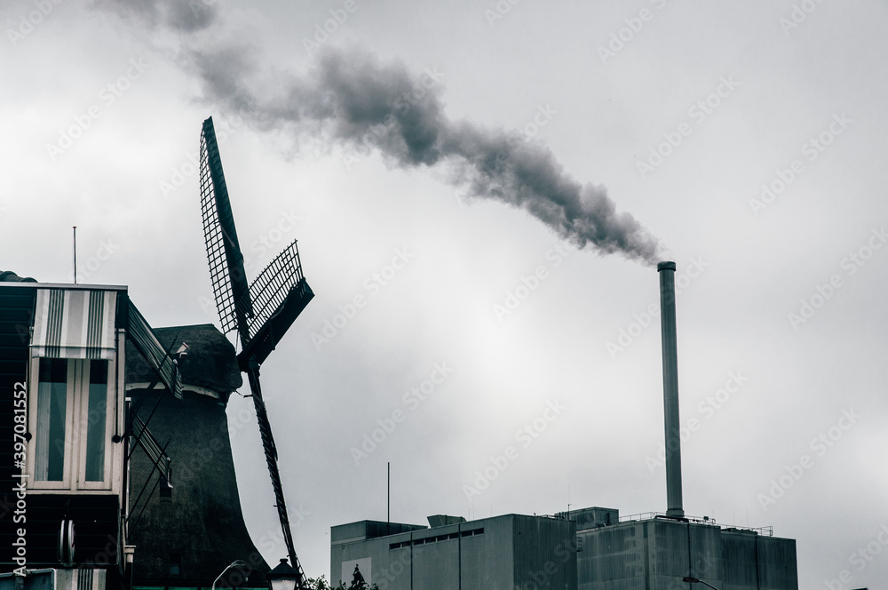 Windmill and industrial chimney of Olam Cocoa Factory in a dark and ...
