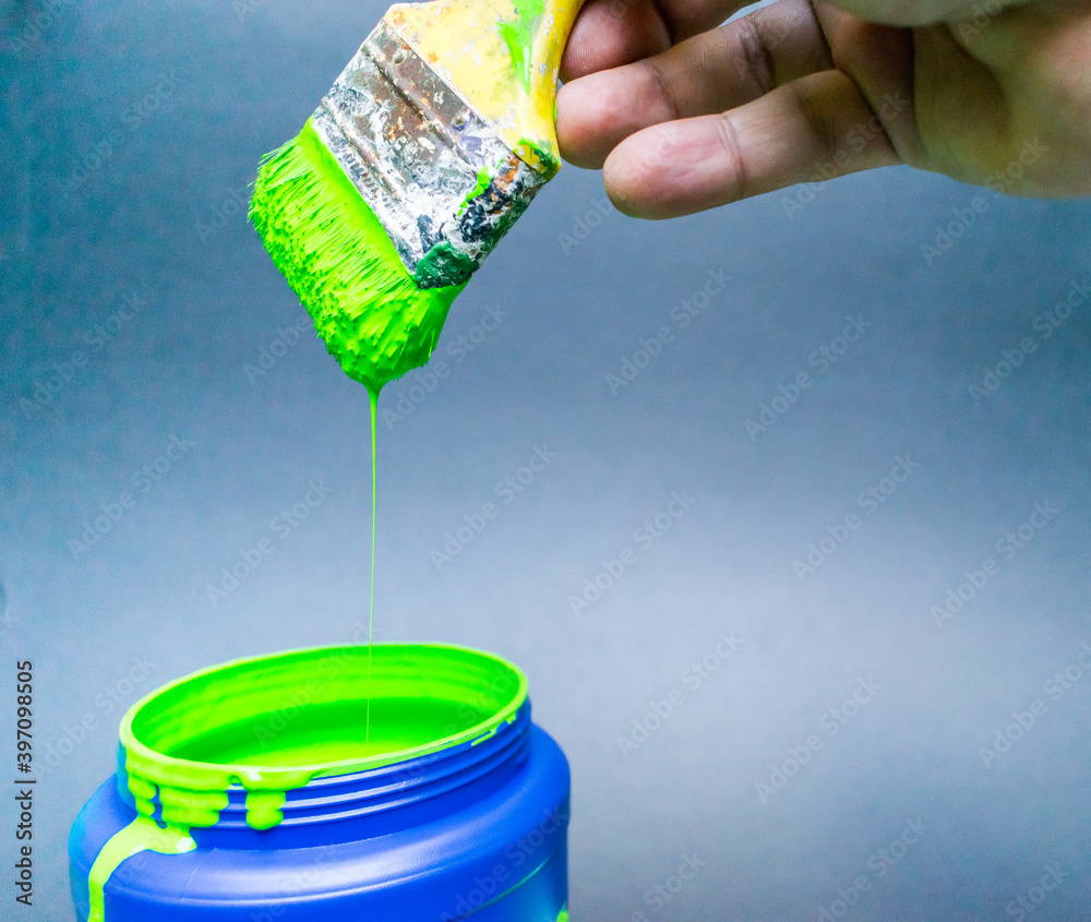 hand grabbing a brush full of green paint, from a paint pot Stock Photo ...