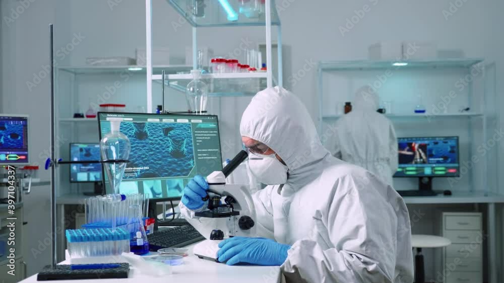 Scientist in ppe suit working in laboratory using modern microscope ...