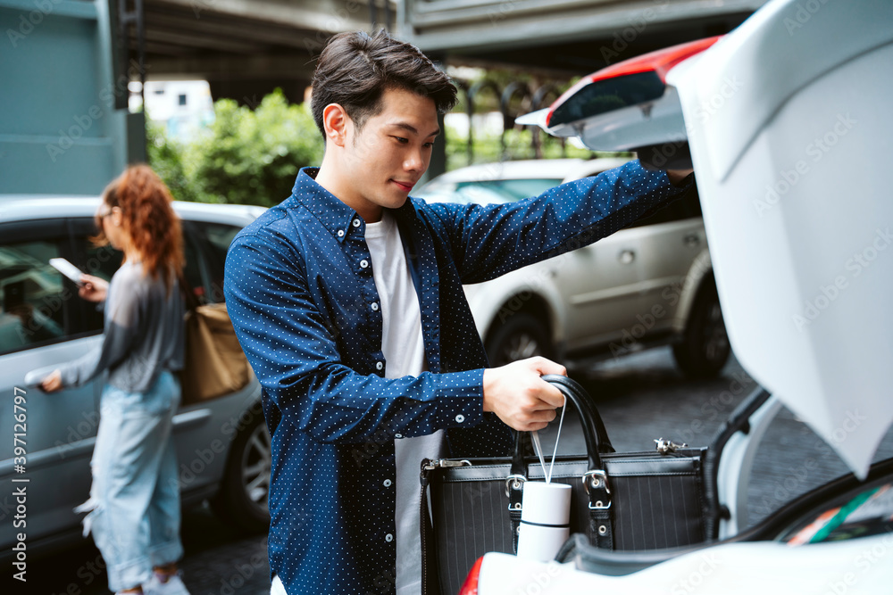 Asian man putting luggage and bag in trunk car. Stock Photo | Adobe Stock