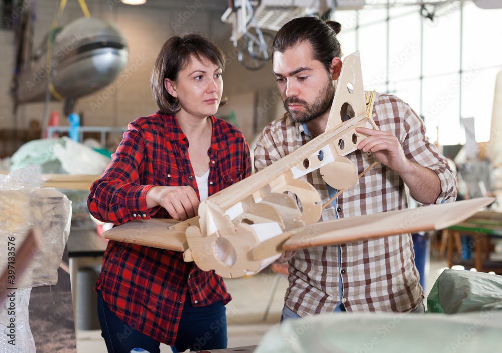 Female and male hobbyists engaged in creating plane models in aircraft ...