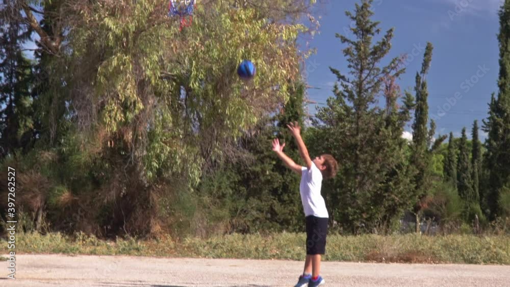 Caucasian boy, takes a shot behind the hoop , at alley basketball court ...