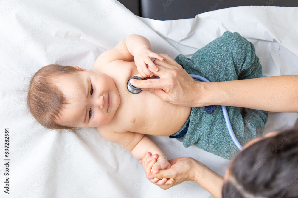 Little beautiful baby having a medical examination by a woman ...