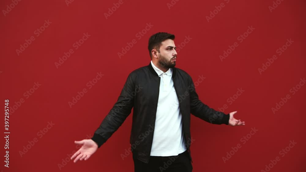 Confused bearded man in casual clothes stands against the background of ...