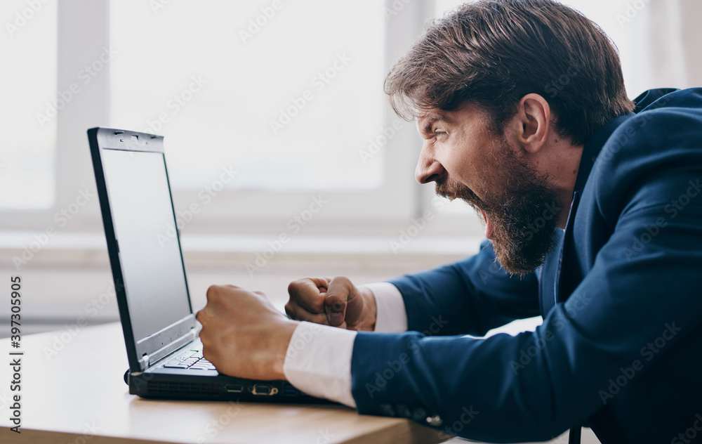 business man at his desk in a suit in front of laptop communication ...