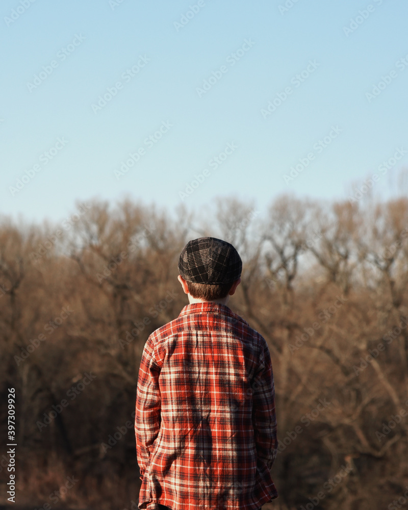 Boy Standing Alone Looking at Trees Outside Stock Photo | Adobe Stock