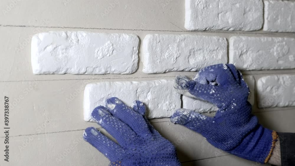 Gypsum brick. Worker laying white brick tiles on wall in room. Texture ...