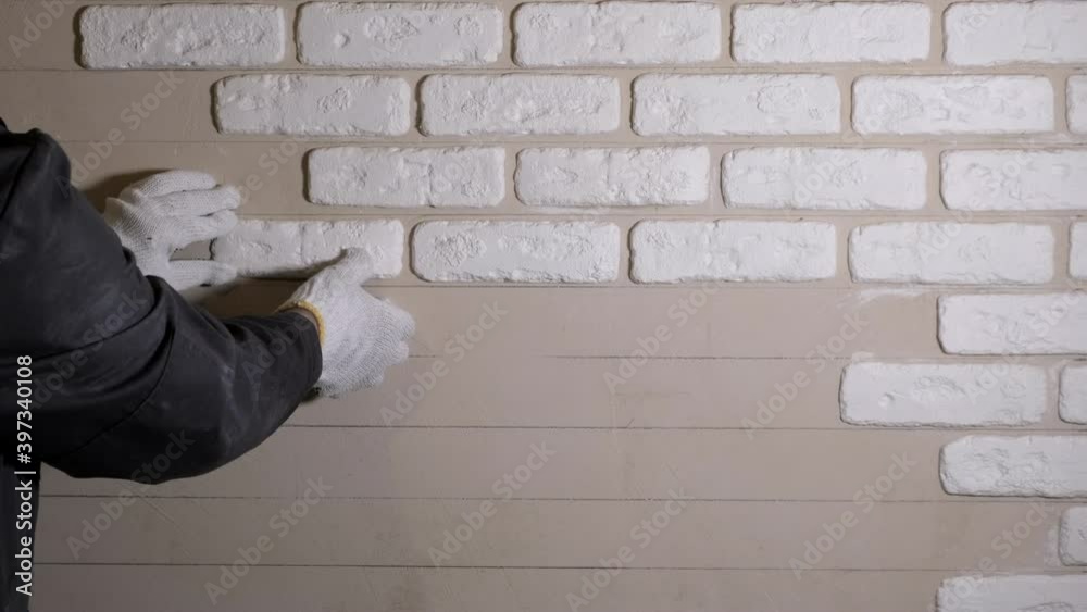 Video Stock Gypsum brick. Worker laying white brick tiles on wall in ...