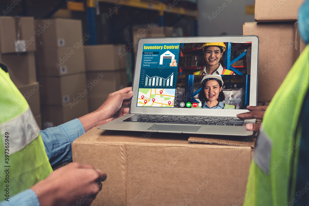 Warehouse staff talking on video call at computer screen in storage ...