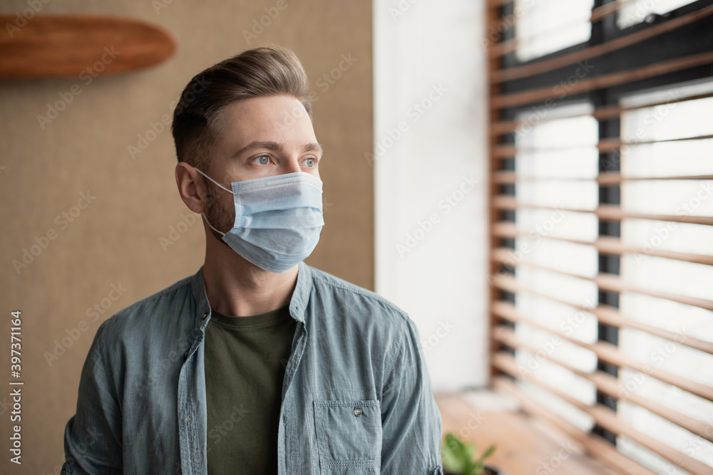 Sad man alone during coronavirus pandemic wearing face mask indoors at ...
