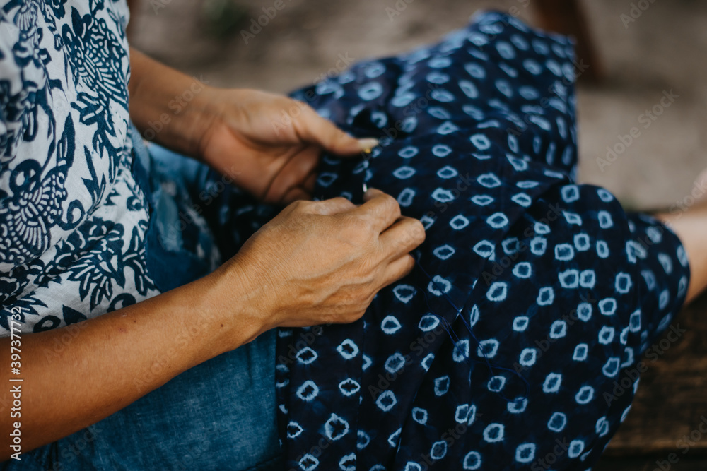 Woman's hands sewing running stitch in blue tribal fabric (dyed indigo ...