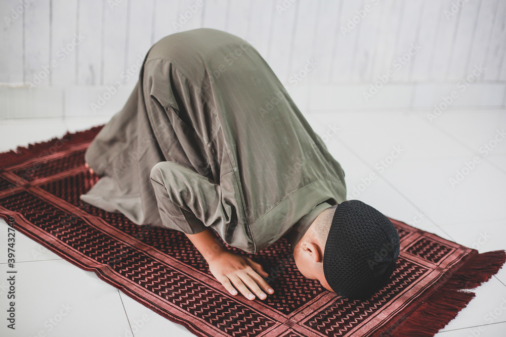 Portrait of asian Muslim Boy wearing traditional costume is doing Salat ...