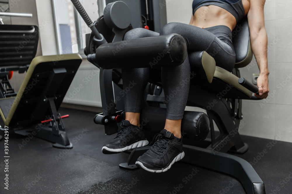 Leg workout. Young athletic woman doing leg extension in exercise ...