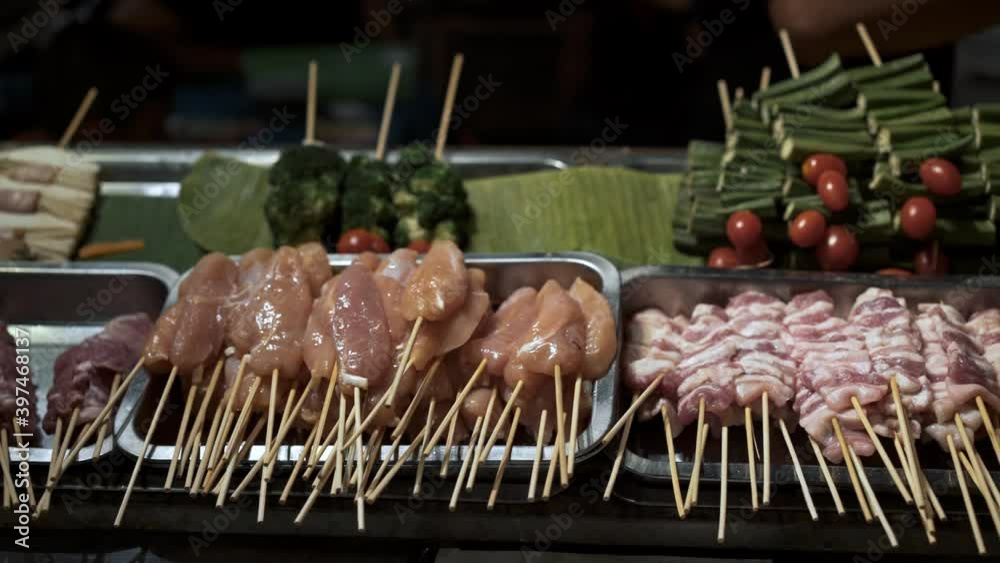 Pan shot left to right of thai raw street meat and food on sticks ...