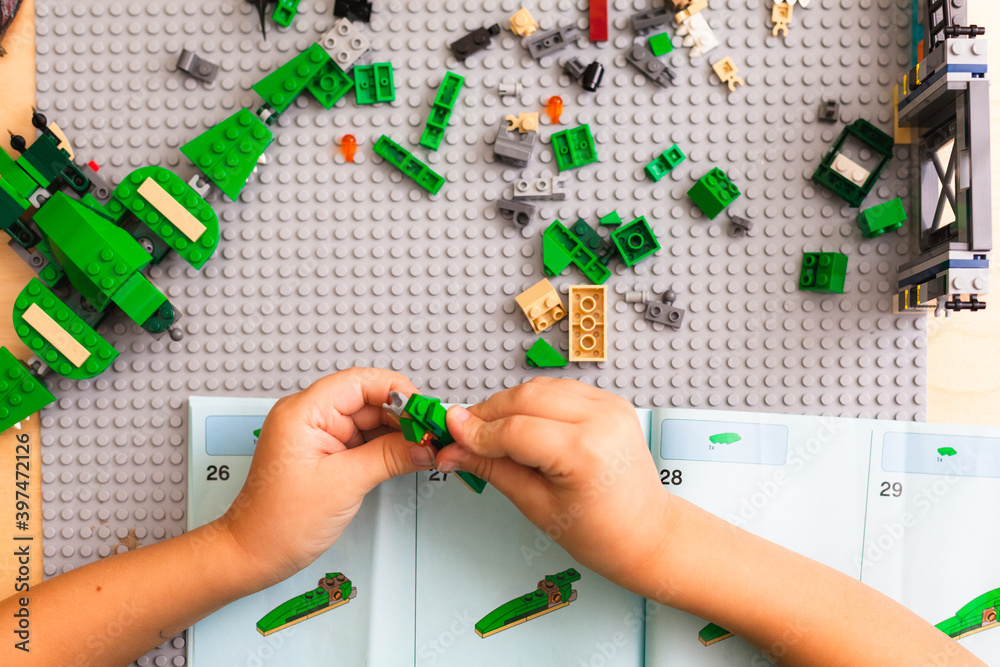 Hands of the child collecting the conductor Lego according to ...