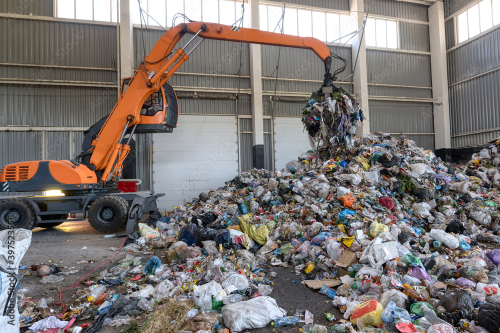 Waste sorting and recycling plant. Loader and grab crane are handling ...