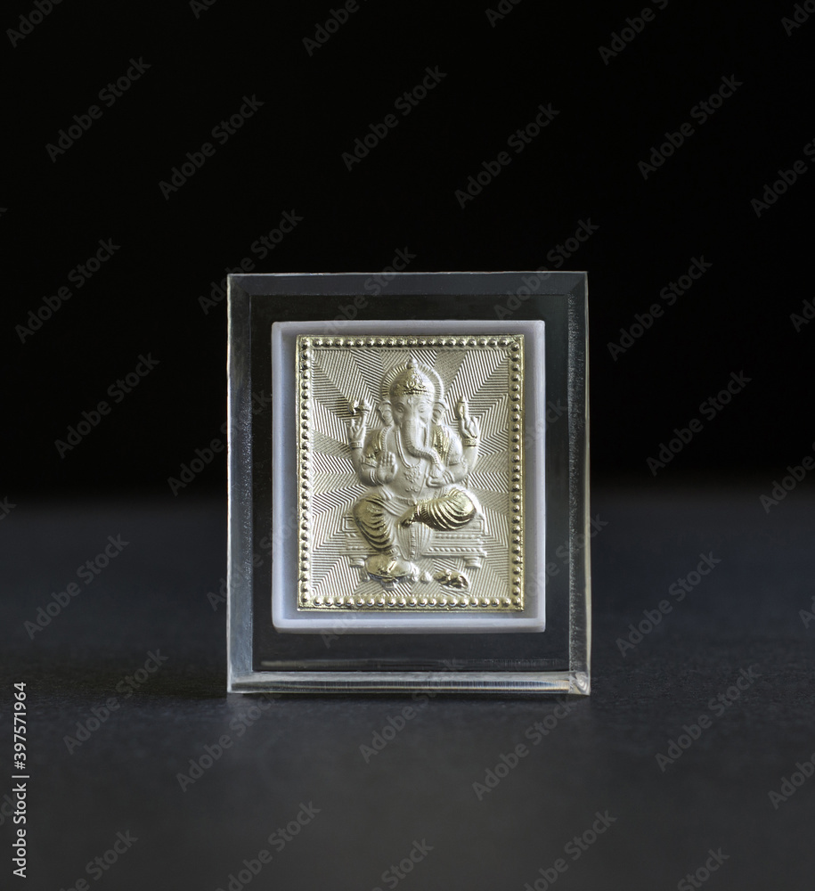 Tiny embossed silver Ganesha frame on black background. Hindu idol ...