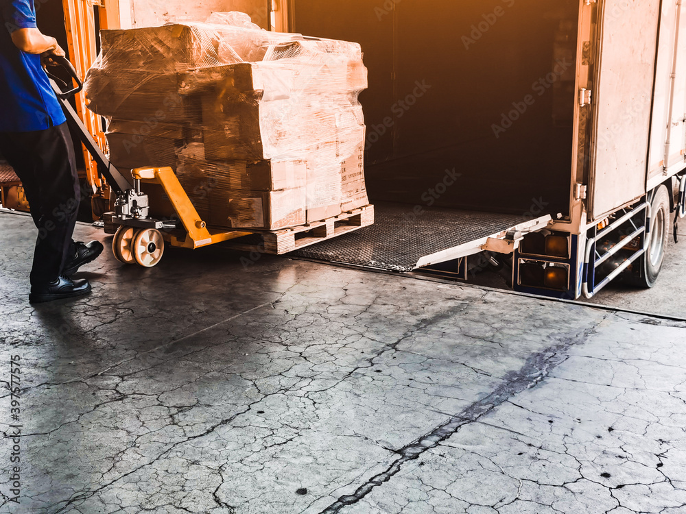 Worker driving forklift loading shipment carton boxes goods on wooden ...