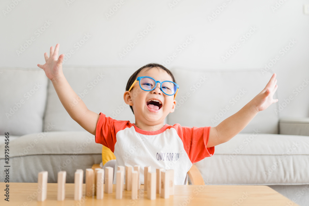 Happy smart nerd toddler asian boy raised hand when he win play wooden ...