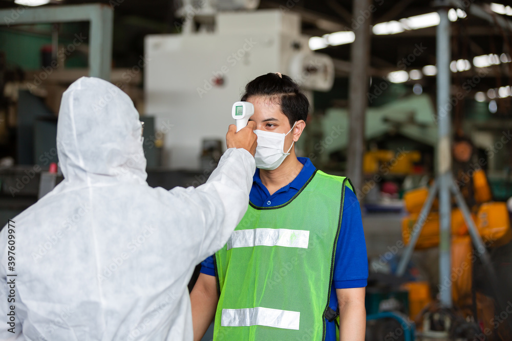 Factory workers in white protection suit disinfecting using infrared ...