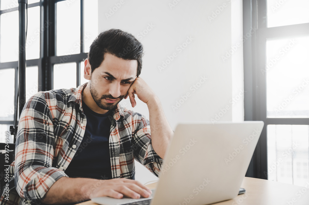 Iranian young man seriously working on computer laptop. He thinking ...