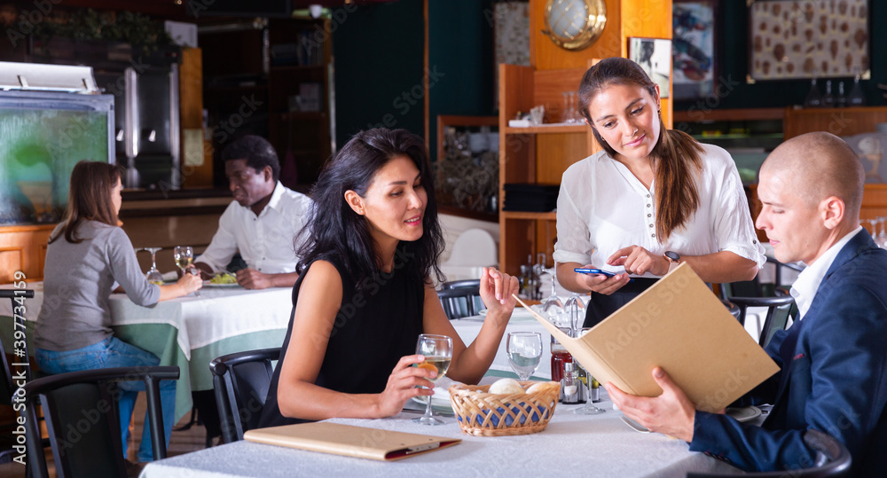 Polite young waitress taking order in restaurant, helping elegant ...