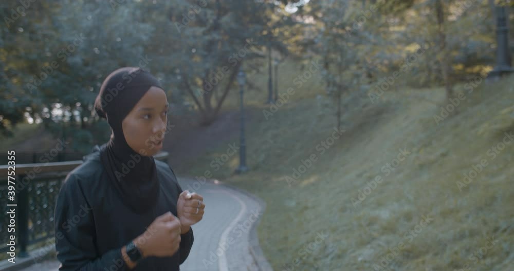 Crop view of young pretty muslim woman in sports suit boxing alone ...