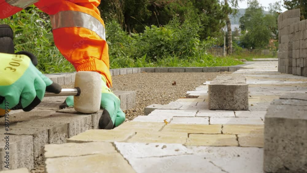 Construction worker. Builder laying paving slabs on the street. Mason ...