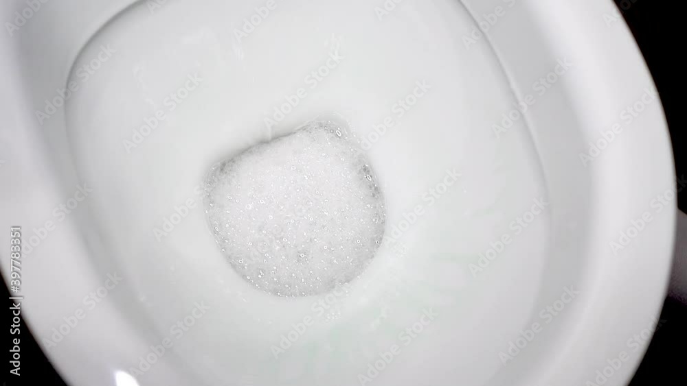 Flush the toilet close-up. White clean toilet, flushing water large ...