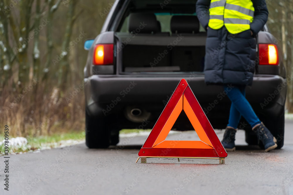 Close-up of an orange triangle emergency stop sign stands on the road ...