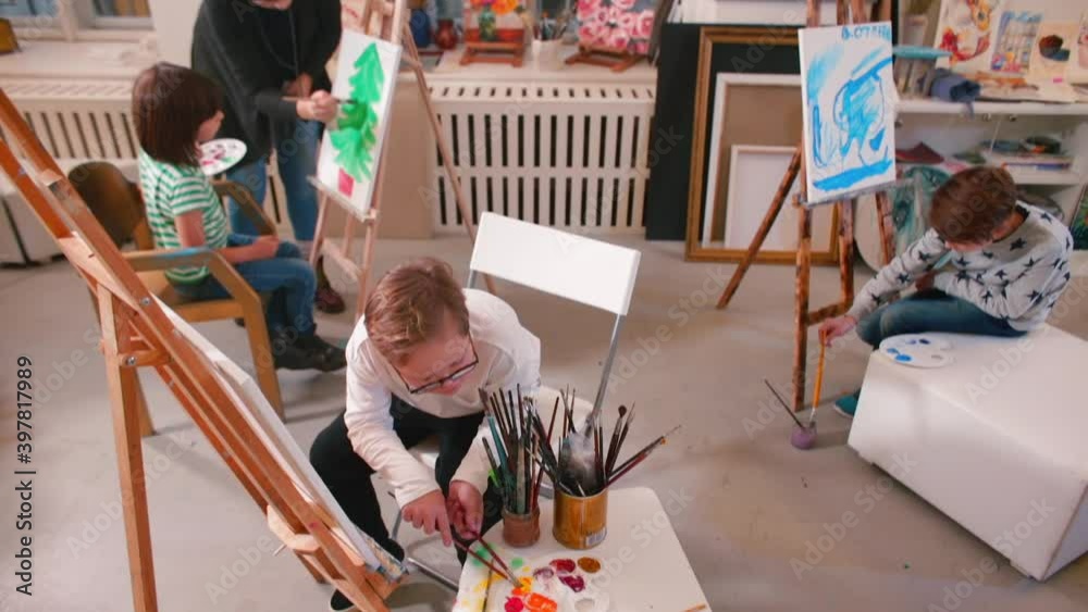 A lesson in an art school, children sit at easels, paint with paints, a ...