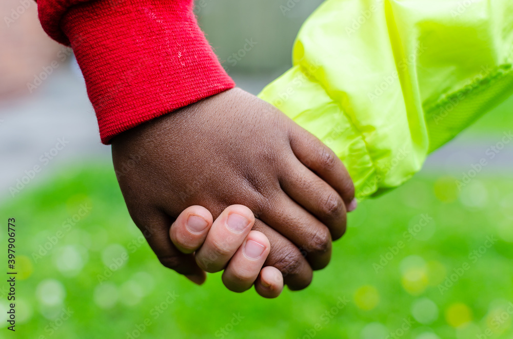 Two children of different races holding hands together. Photo shows ...