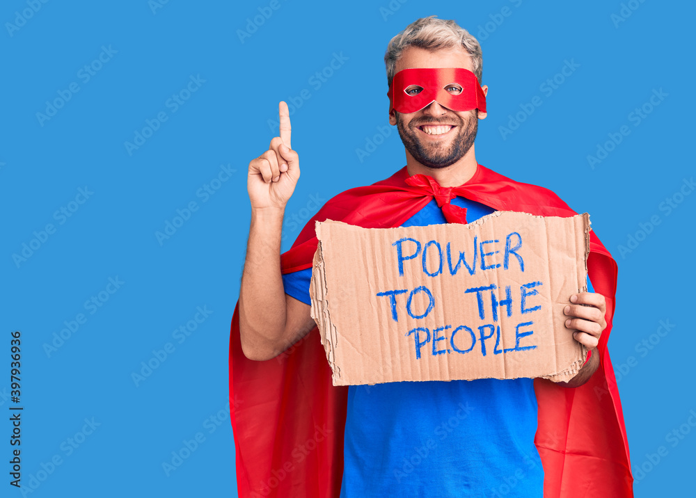 Young blond man wearing super hero custome holding power to the people ...