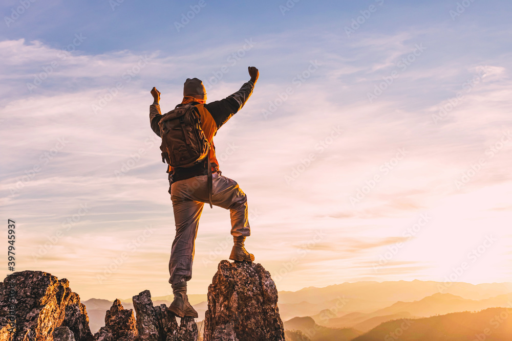 hiker with backpack at the top of a rock with his hands raised enjoy ...