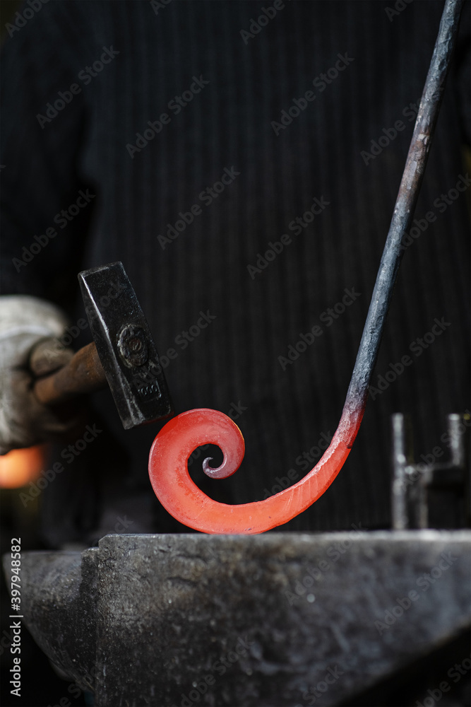 The blacksmith twists the spiral with a sledgehammer, placing a red-hot ...