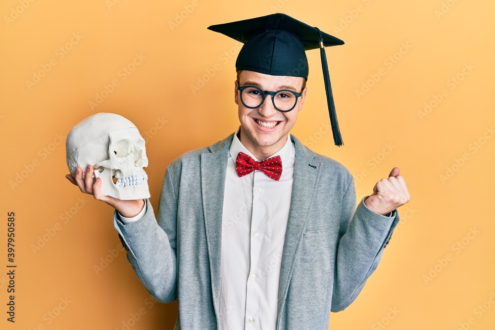 Young caucasian nerd man wearing glasses and graduation cap holding ...
