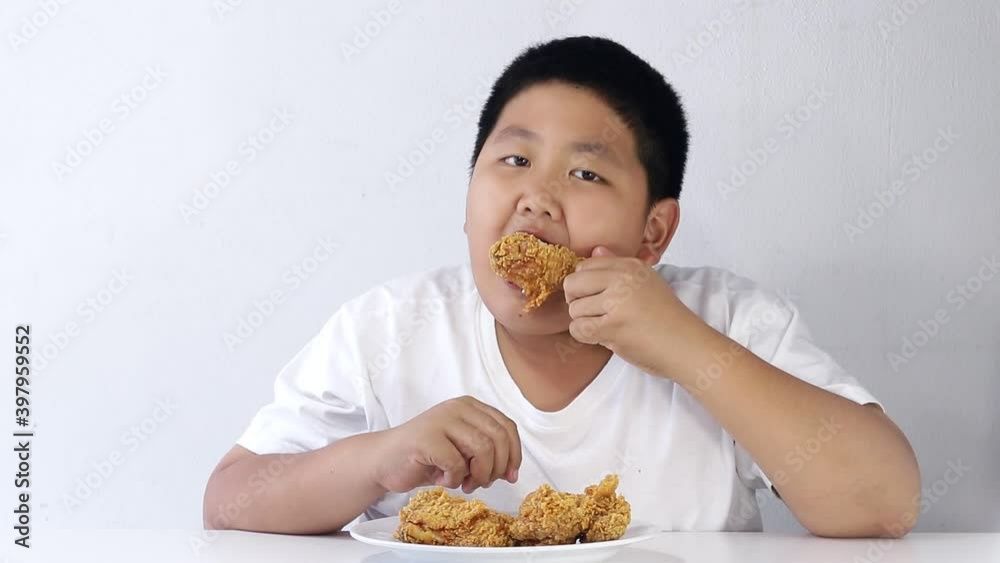 Asian fat boy eats fried chicken Wear a white shirt. Concepts of child ...
