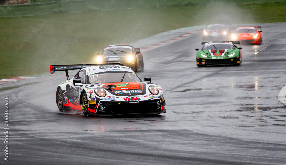 Wet race motorsport racing cars spraying water at curve on asphalt ...