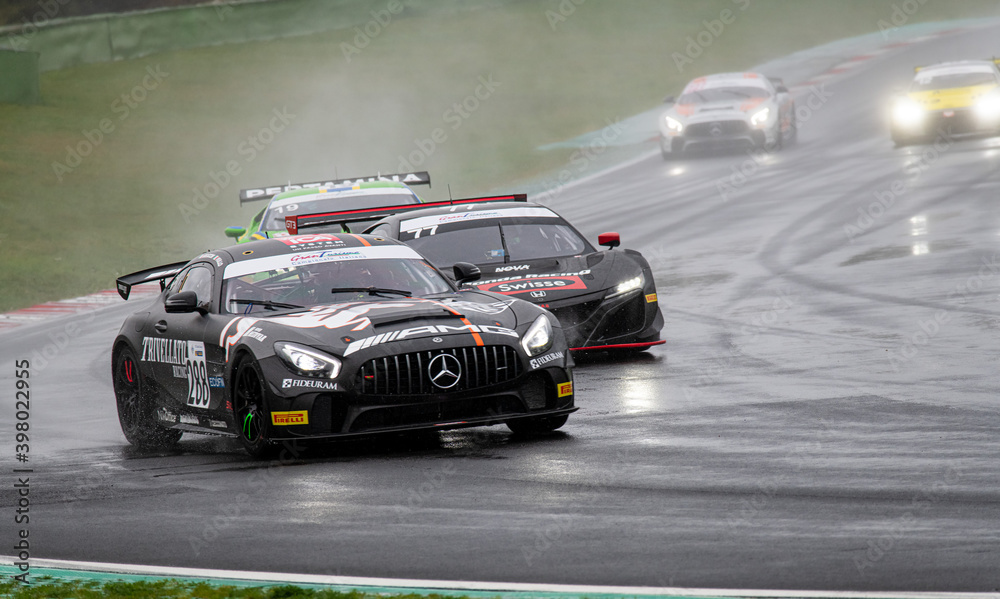 Wet race motorsport racing cars spraying water at curve on asphalt ...
